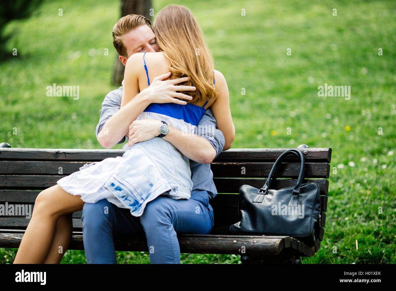 Dating couple sitting on bench in city park Stock Photo - Alamy