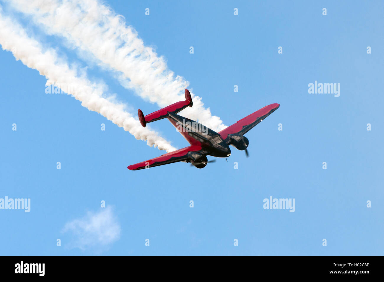 A black and red airplane flying with smoke Stock Photo - Alamy