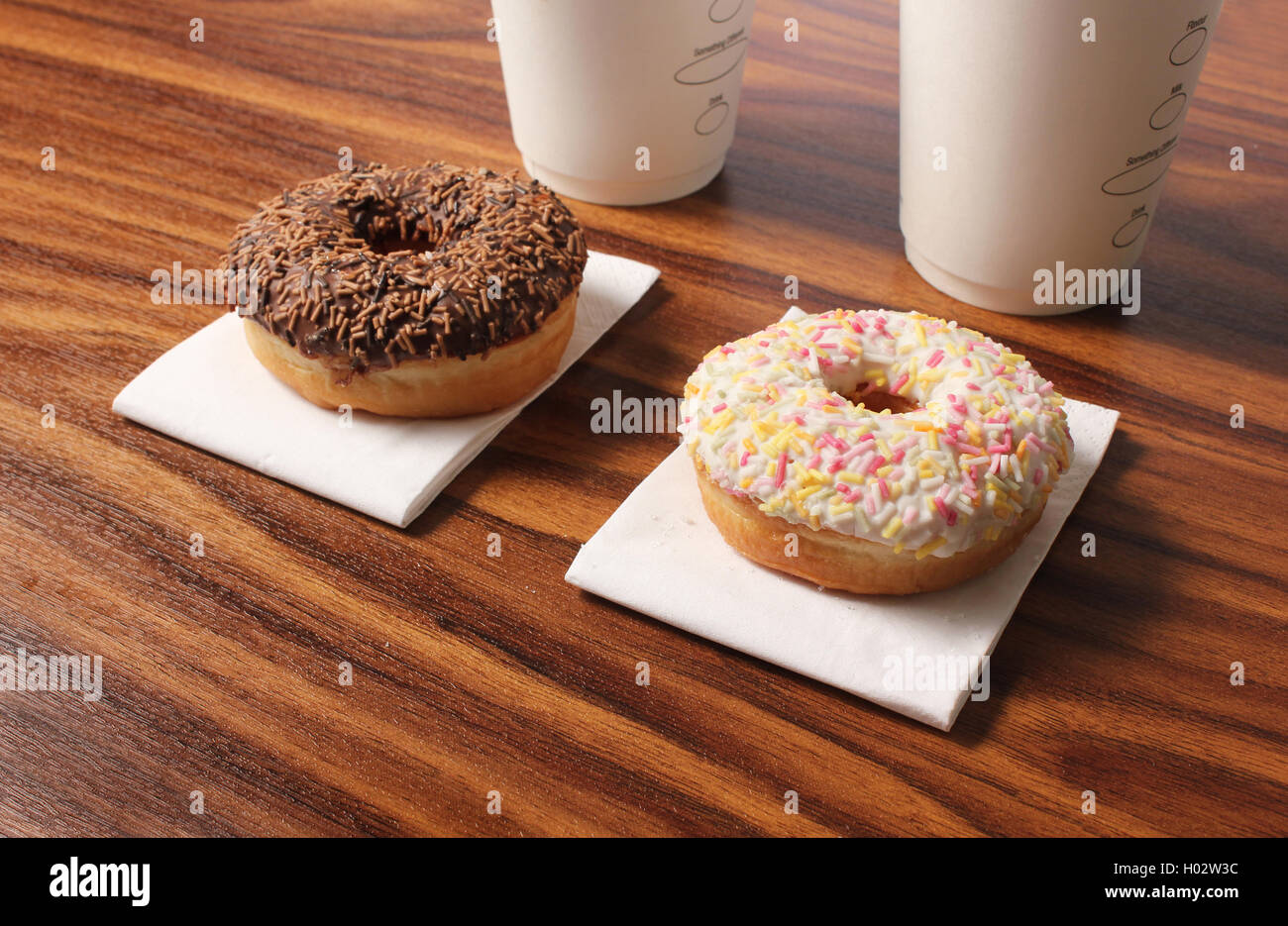 Two donuts sitting on a napkin on an office desk with takeawy coffee ...
