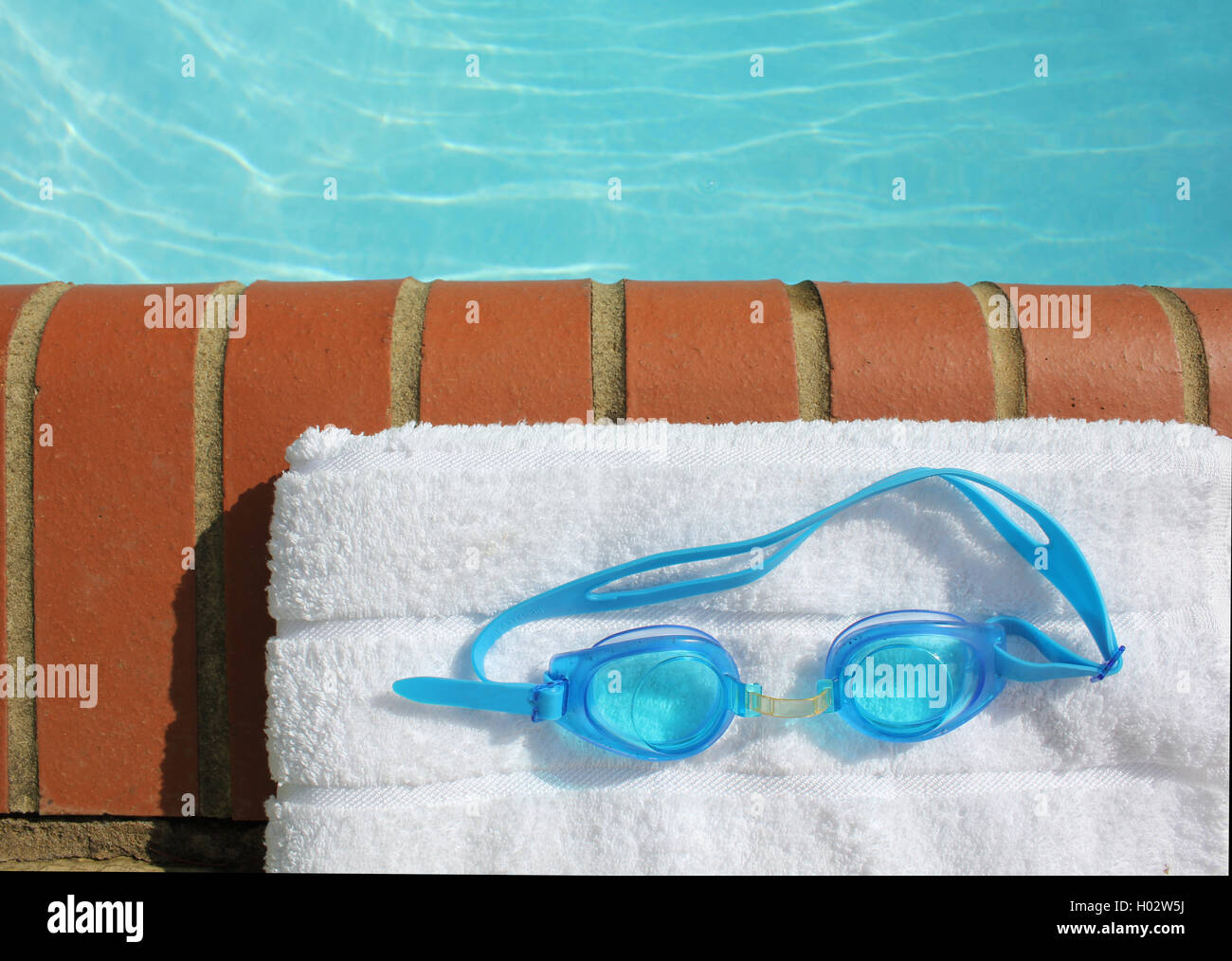 a pair of swimming goggles by a pool on a white towel Stock Photo - Alamy
