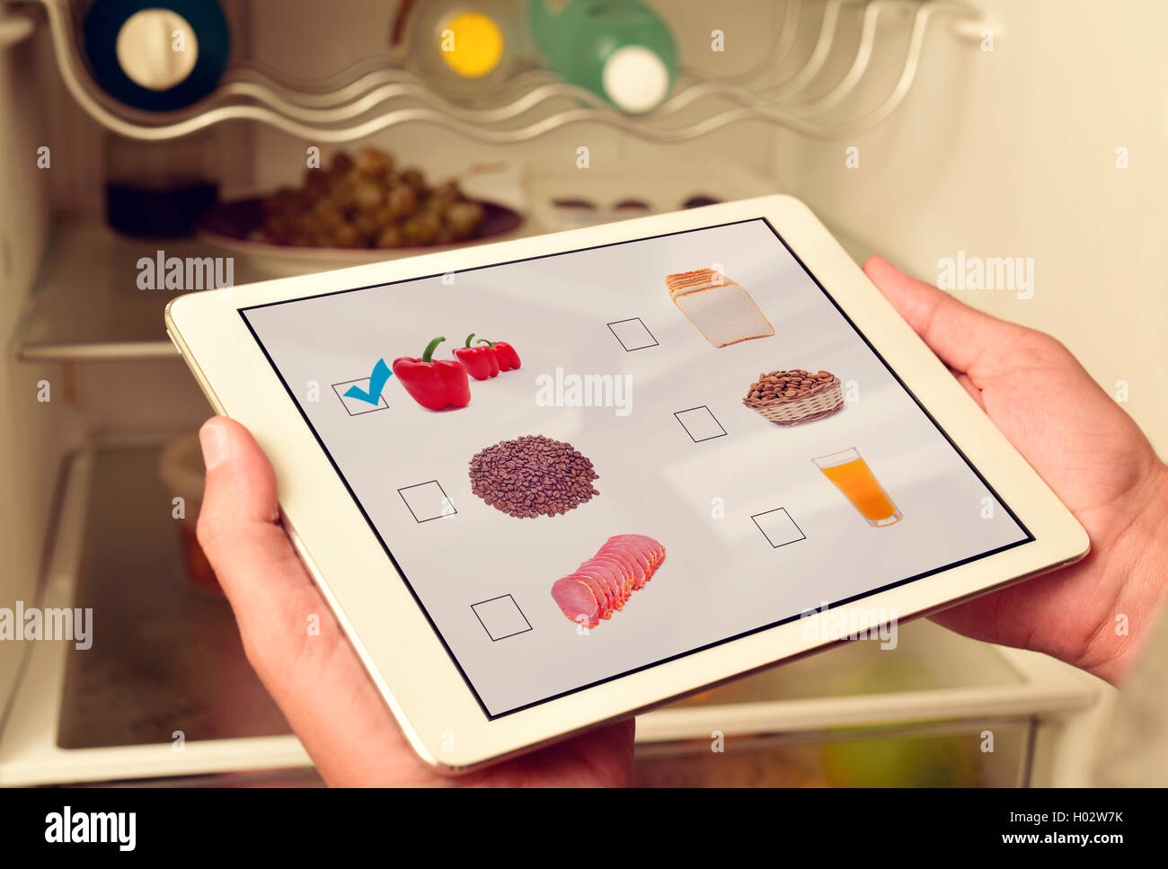 young man making his shopping list in his tablet computer, with ...