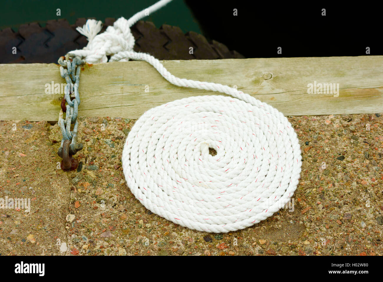 Coiled white rope on stone and wood pier Stock Photo - Alamy