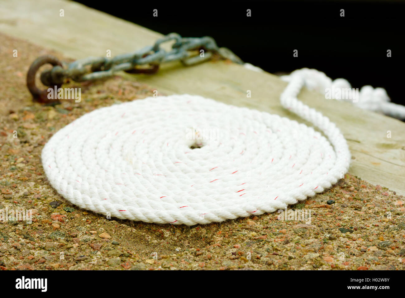 Coiled white rope on stone and wood pier Stock Photo - Alamy