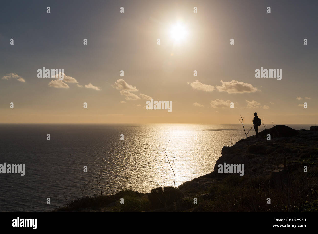 Silhouette of the girl standing at the cliff, watching at the sea at ...