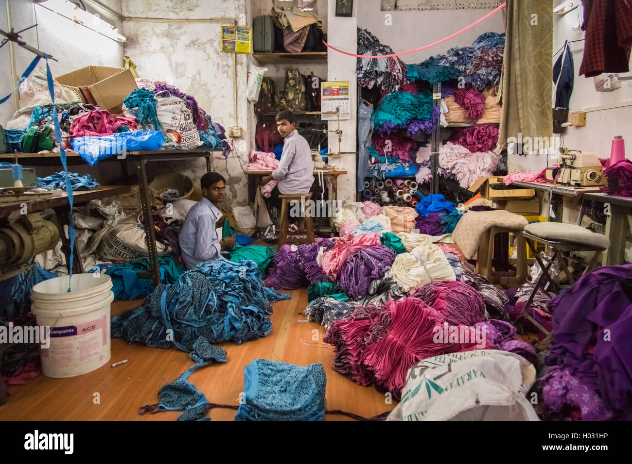 MUMBAI, INDIA - 12 JANUARY 2015: Two men work in small underwear ...