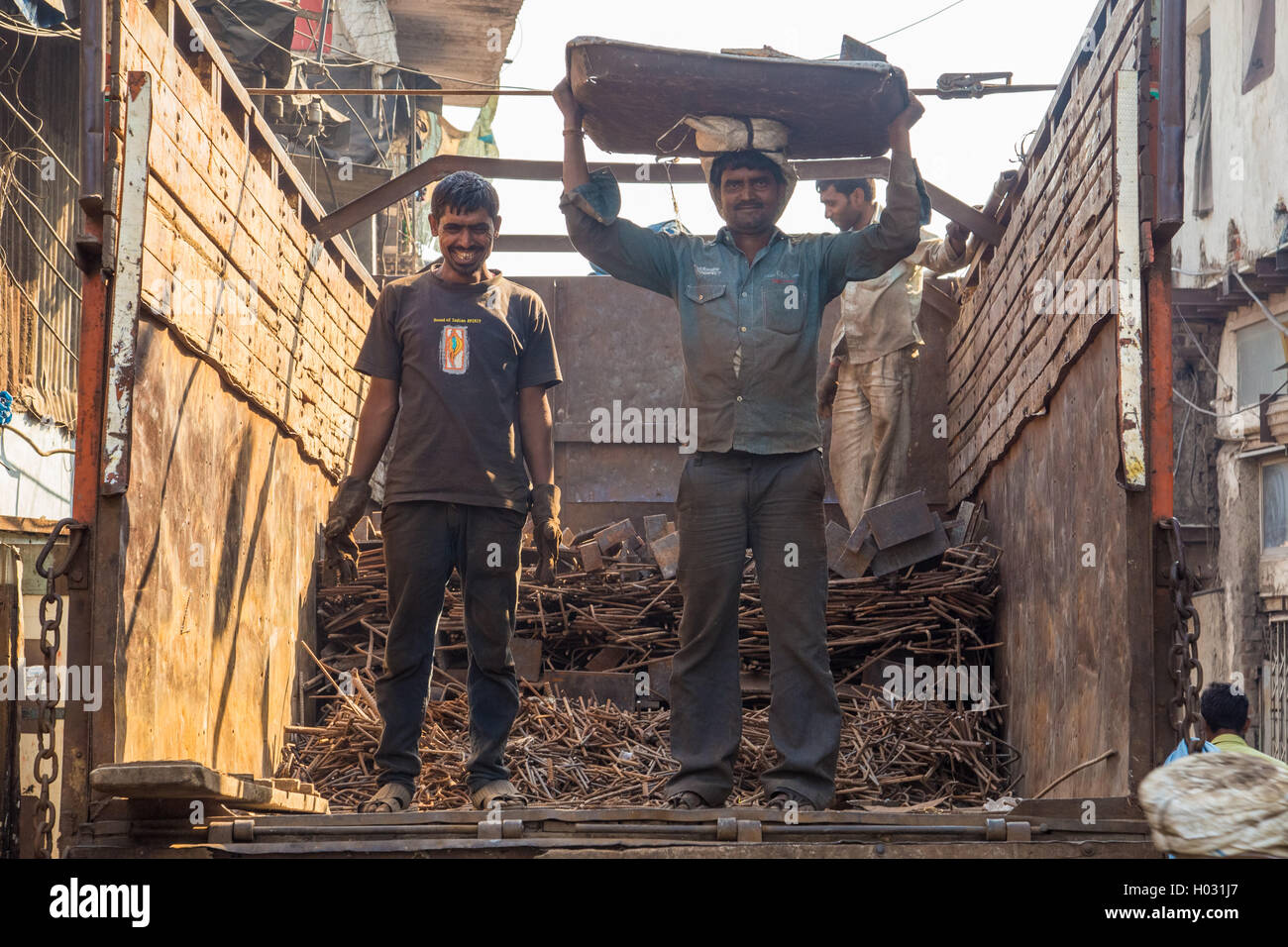 MUMBAI, INDIA - 12 JANUARY 2015: Two men load metal on back of ...