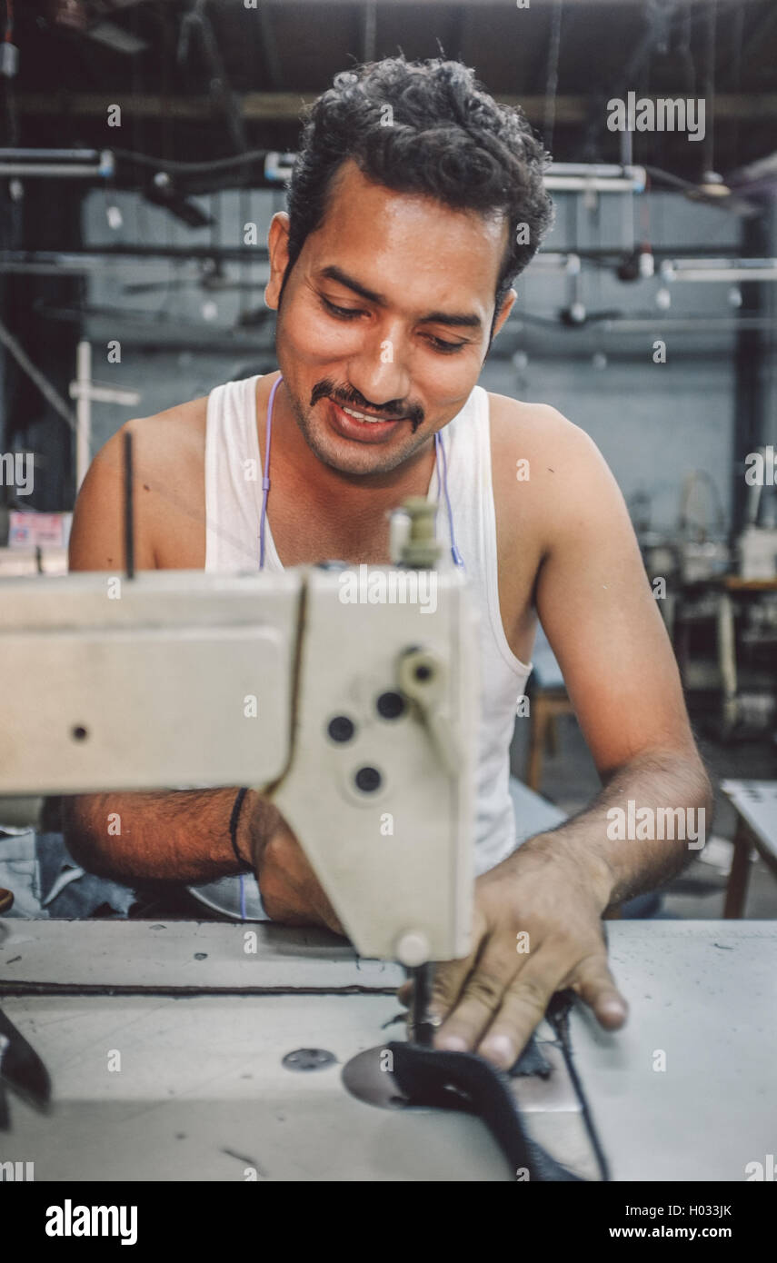 MUMBAI, INDIA - 12 JANUARY 2015: Indian worker sews in clothing factory ...