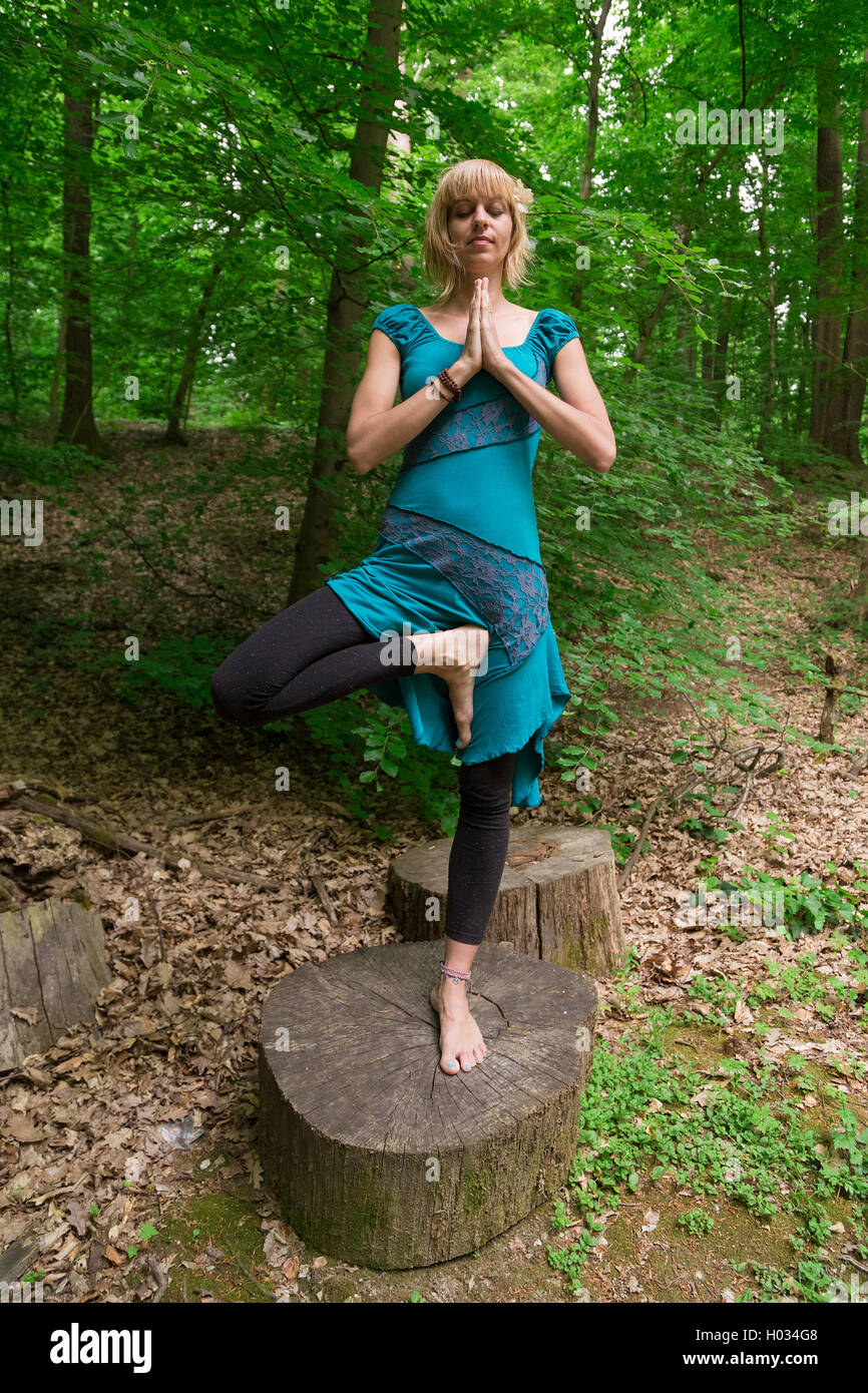 Young woman practicing yoga tree pose in forest Stock Photo - Alamy