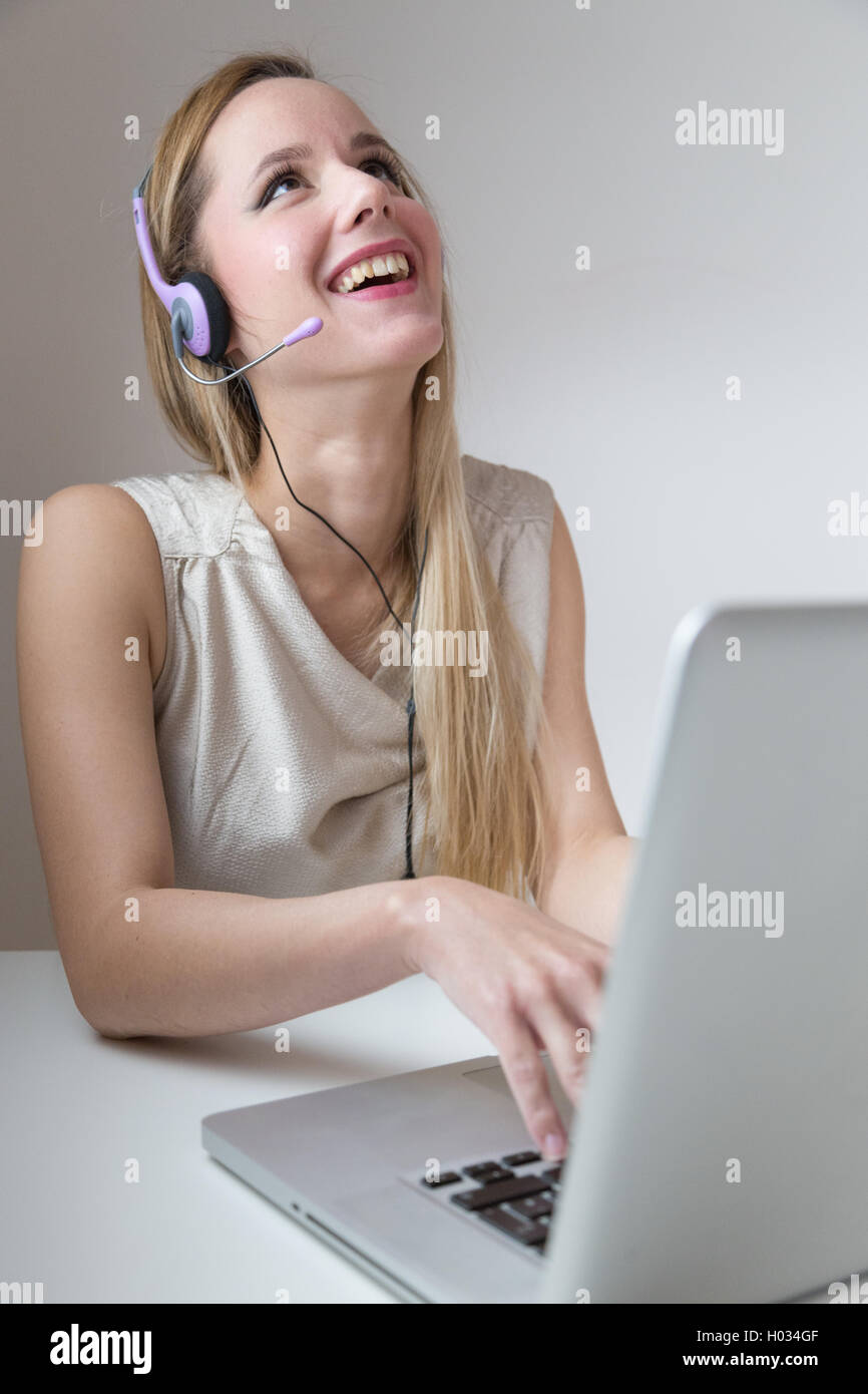 Attractive smiling blonde woman with headset working on a laptop Stock ...