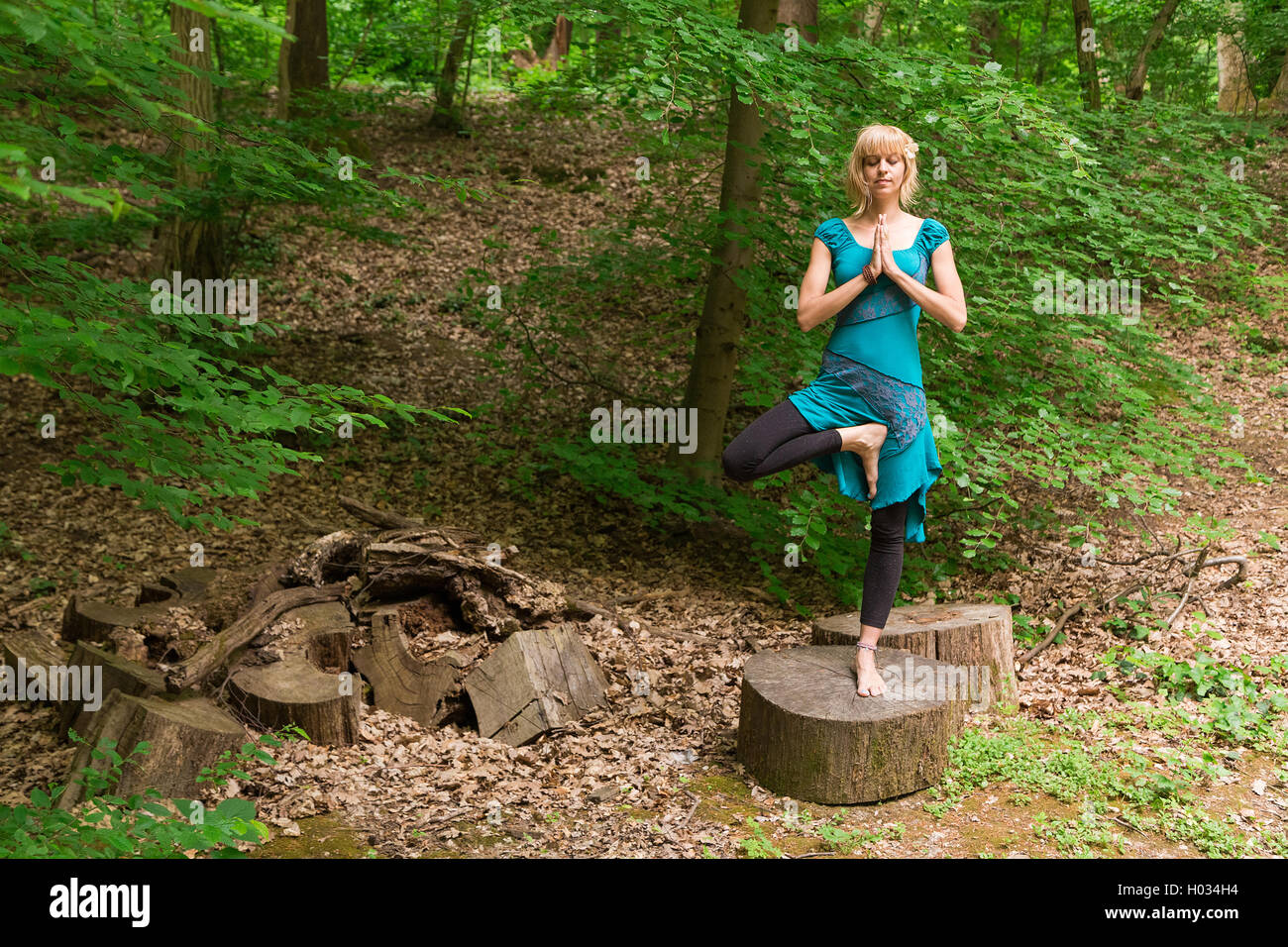 Young woman practicing yoga tree pose in forest Stock Photo - Alamy