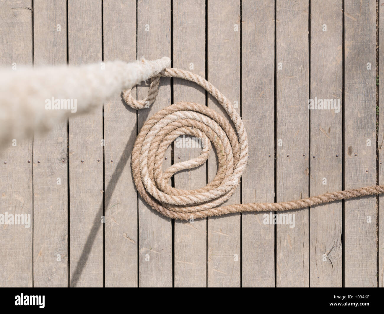 Twisted manila rope on wooden plank floor Stock Photo - Alamy