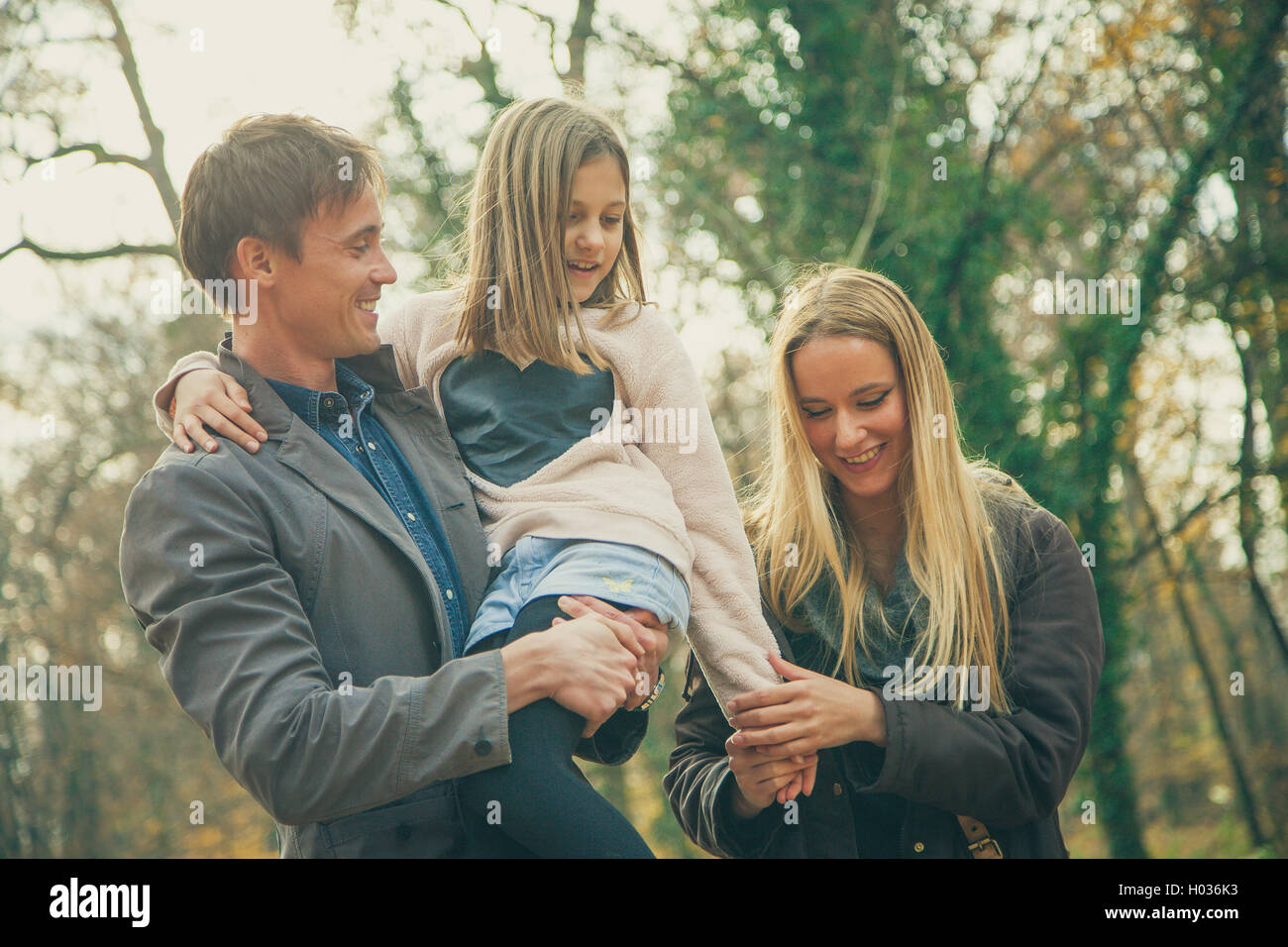 Playful family of three walk in a park on an autumn day Stock Photo - Alamy