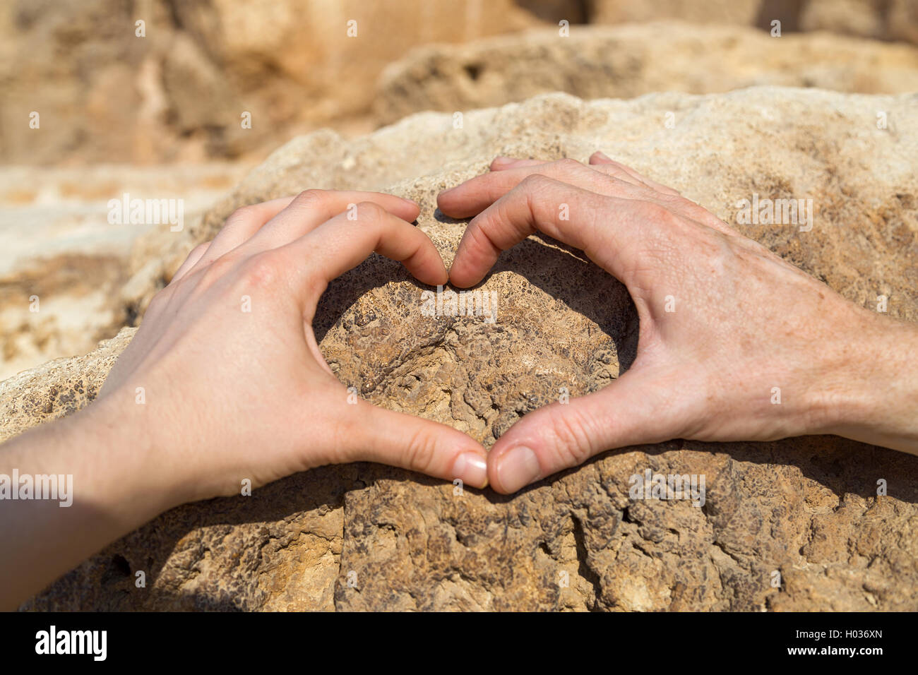 Man and woman making heart shape with their hands on rock Stock Photo ...