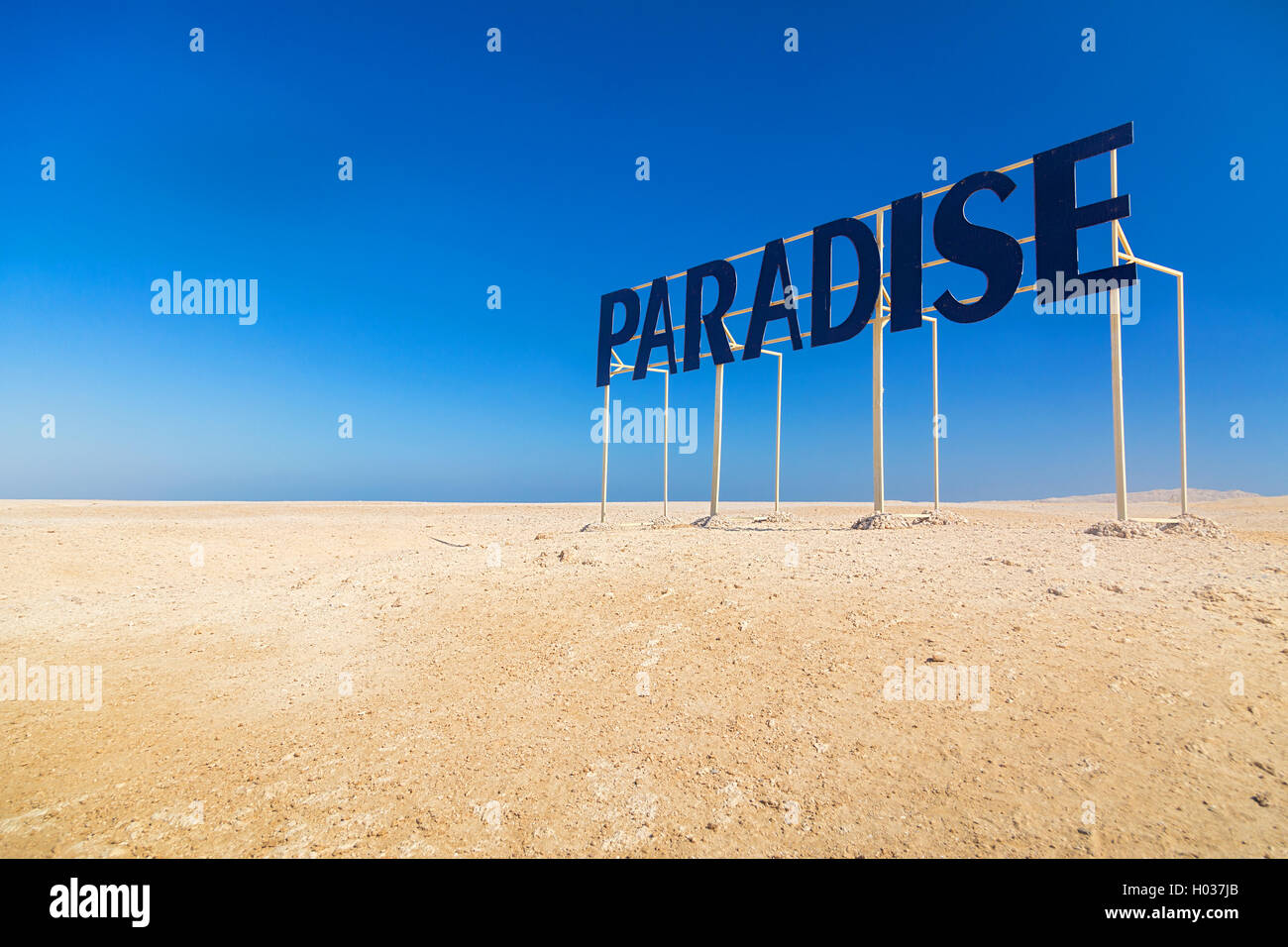 Paradise sign on sand against clear blue sky Stock Photo - Alamy