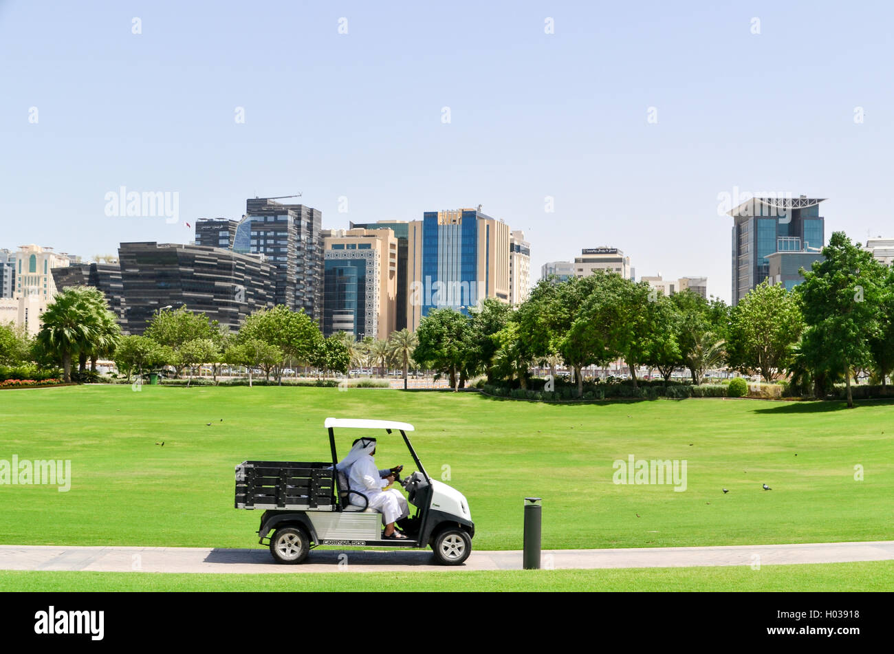 Qataris in the shade of a gold cart driving in a park in the city ...