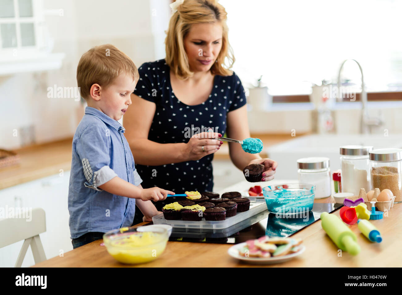 Smart cute child helping mother in kitchen preparing cookies Stock ...