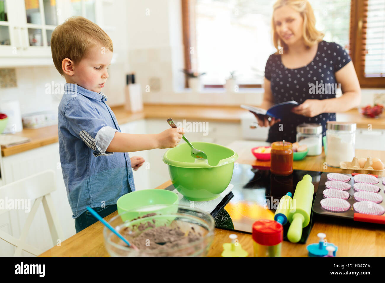 Smart cute child helping mother in kitchen preparing cookies Stock ...