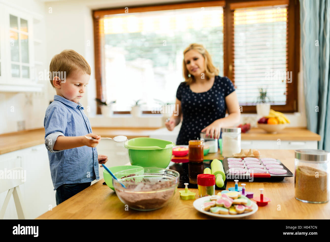 Smart cute child helping mother in kitchen preparing cookies Stock ...