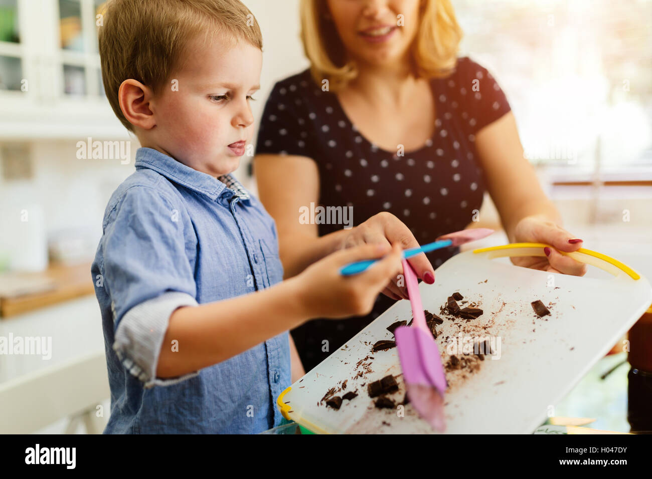 Smart cute child helping mother in kitchen preparing cookies Stock ...