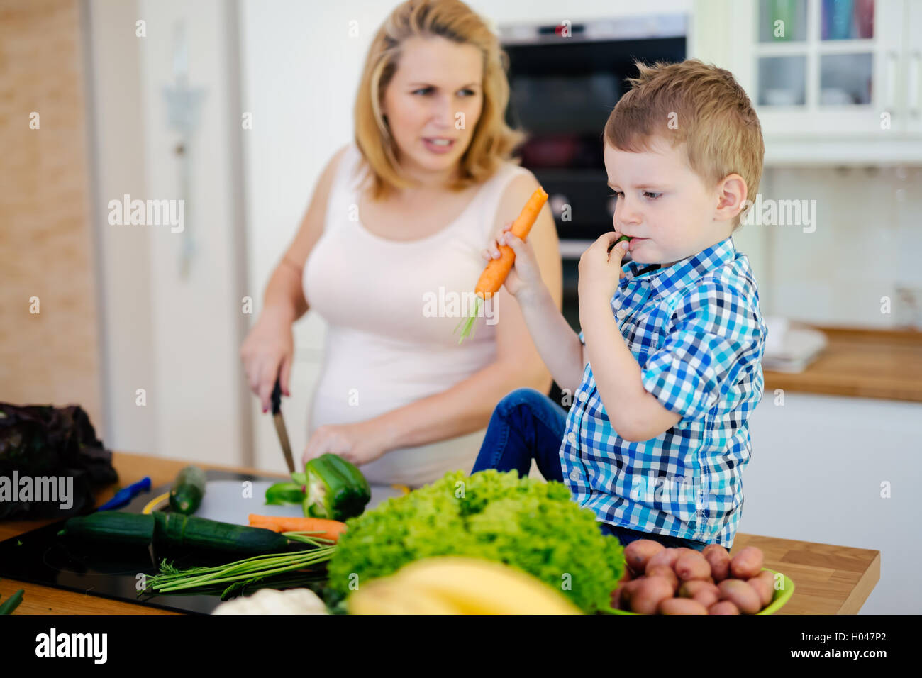 Pregnant mom and child preparing meal and tasting ingredients Stock ...