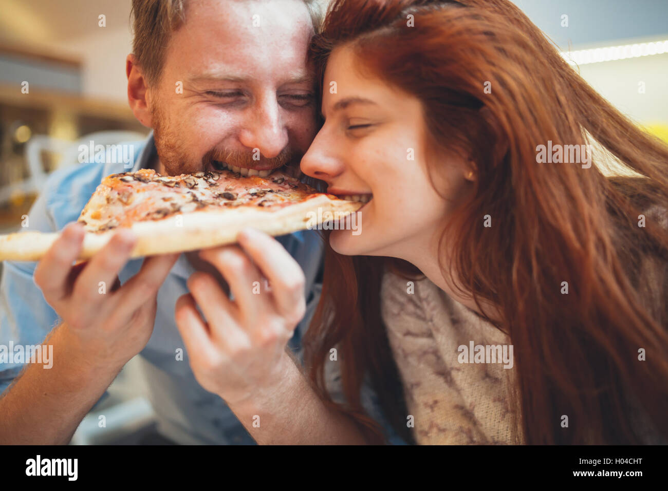 Couple sharing pizza and eating together happily Stock Photo - Alamy