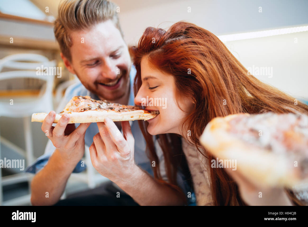 Couple sharing pizza and eating together happily Stock Photo - Alamy