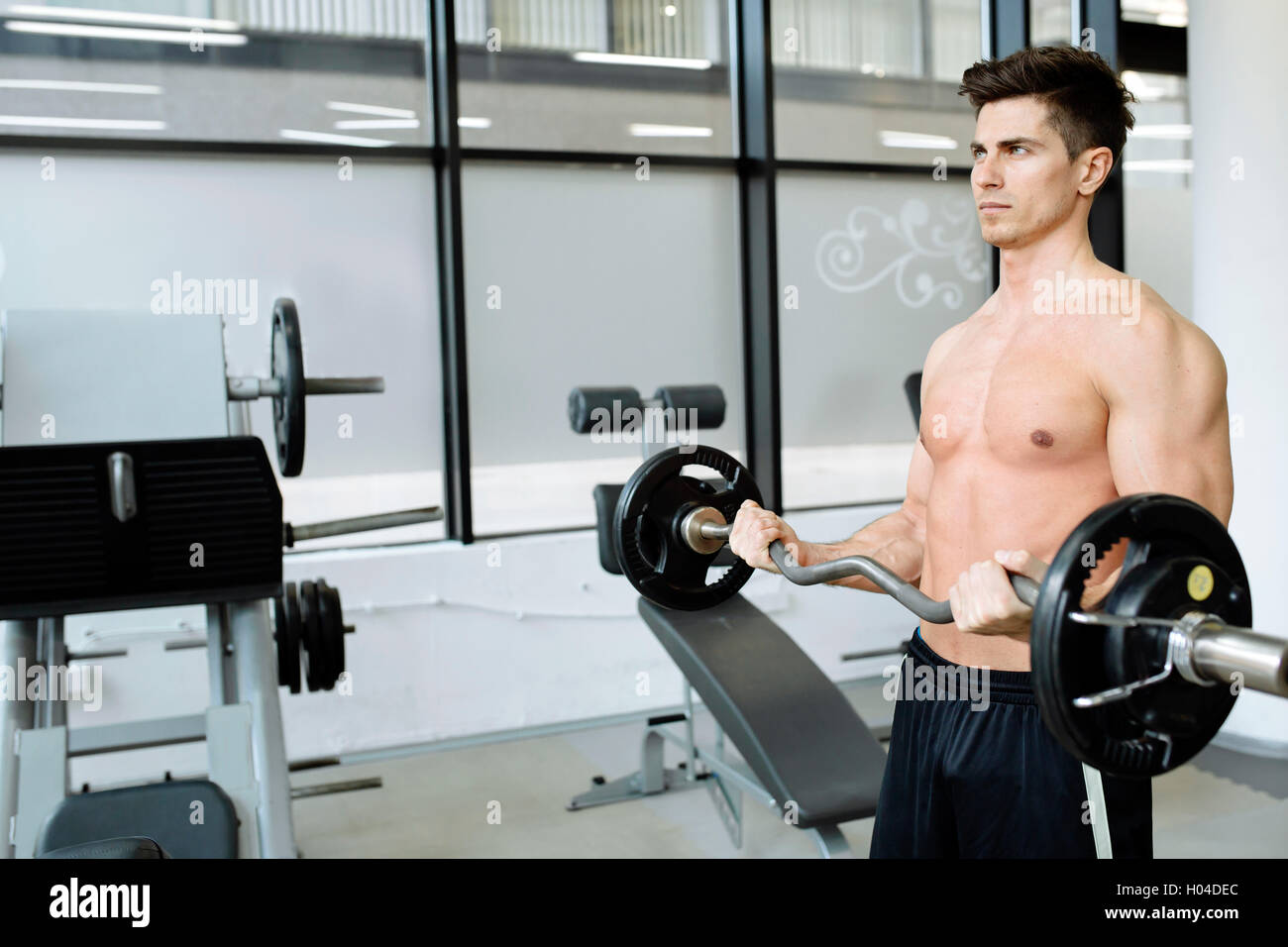 Muscular man bodybuilding in gym, lifting weights Stock Photo - Alamy