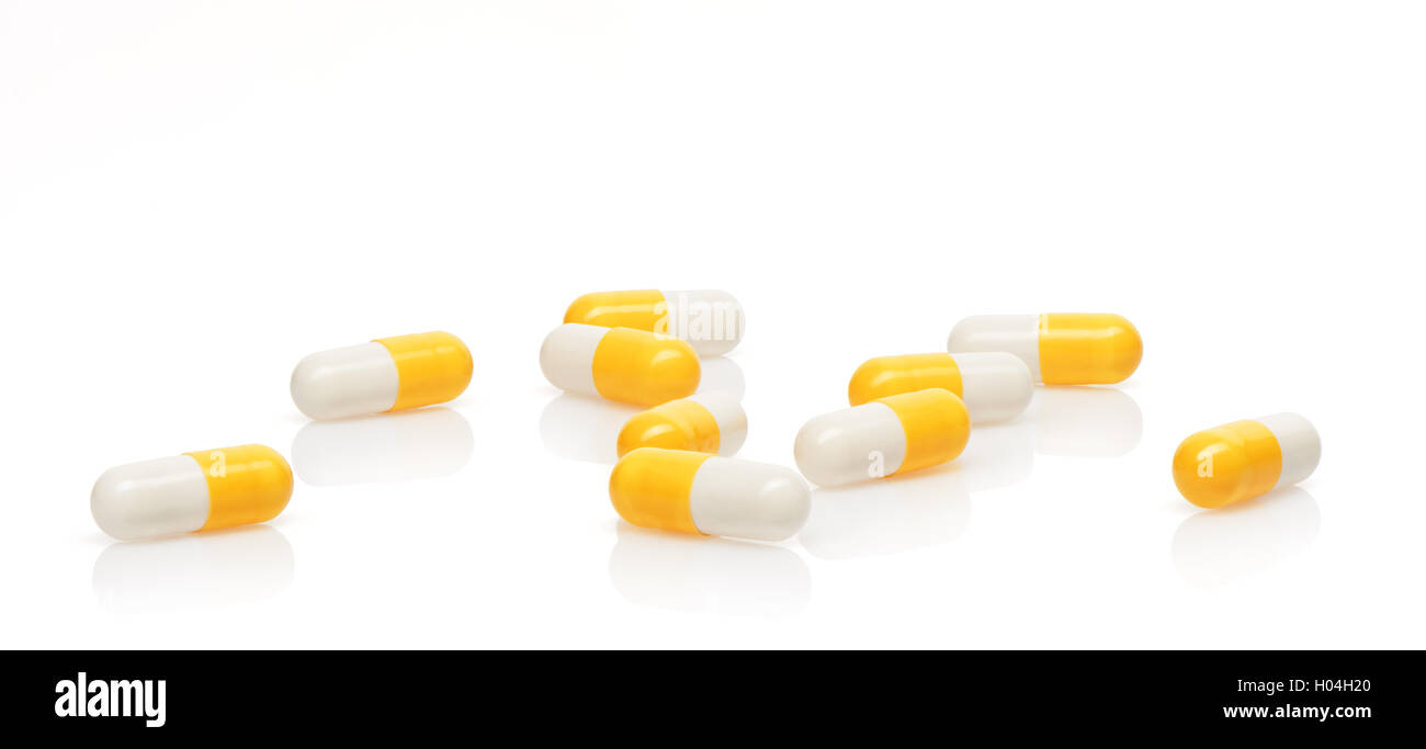 Pile of yellow and white capsules isolated on white background ...