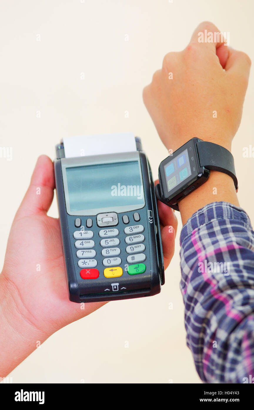 Closeup hand holding credit card payment terminal, another arm wearing ...