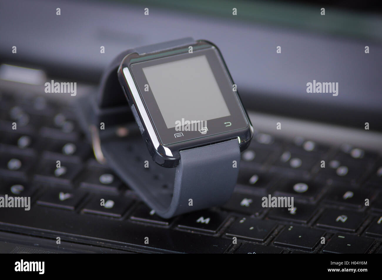 Smartwatch with screen lit up sitting on top of computer keyboard, very ...