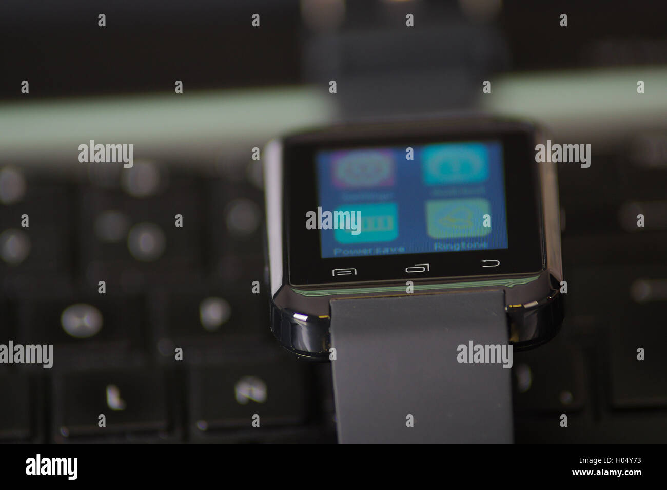 Smartwatch with screen lit up sitting on top of computer keyboard, very ...