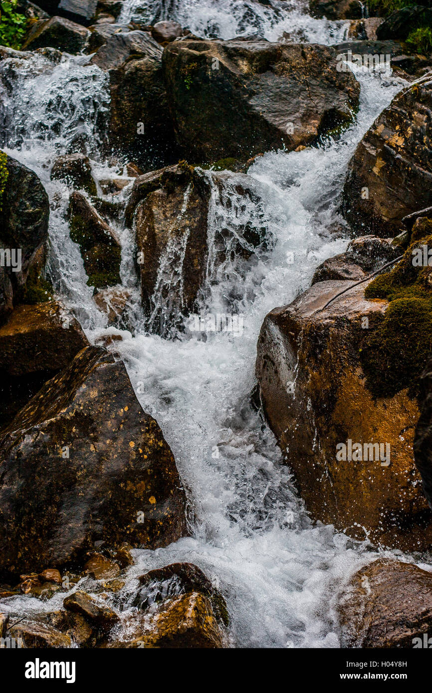 A fresh flowing waterfall in the middle of the alps is drawing its way ...