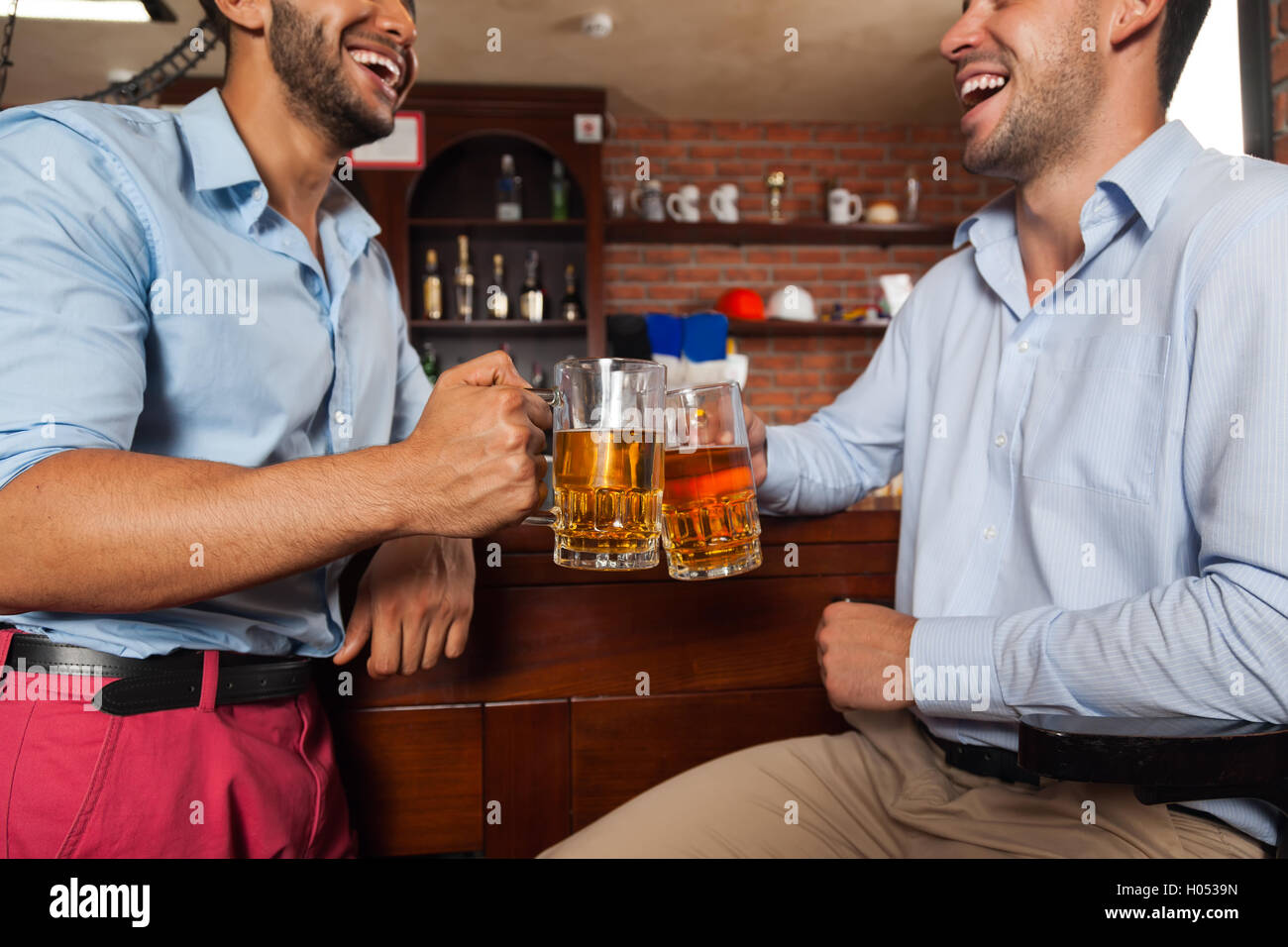 Two Man In Bar Clink Glasses Toasting Sit At Table, Drinking Beer Hold ...
