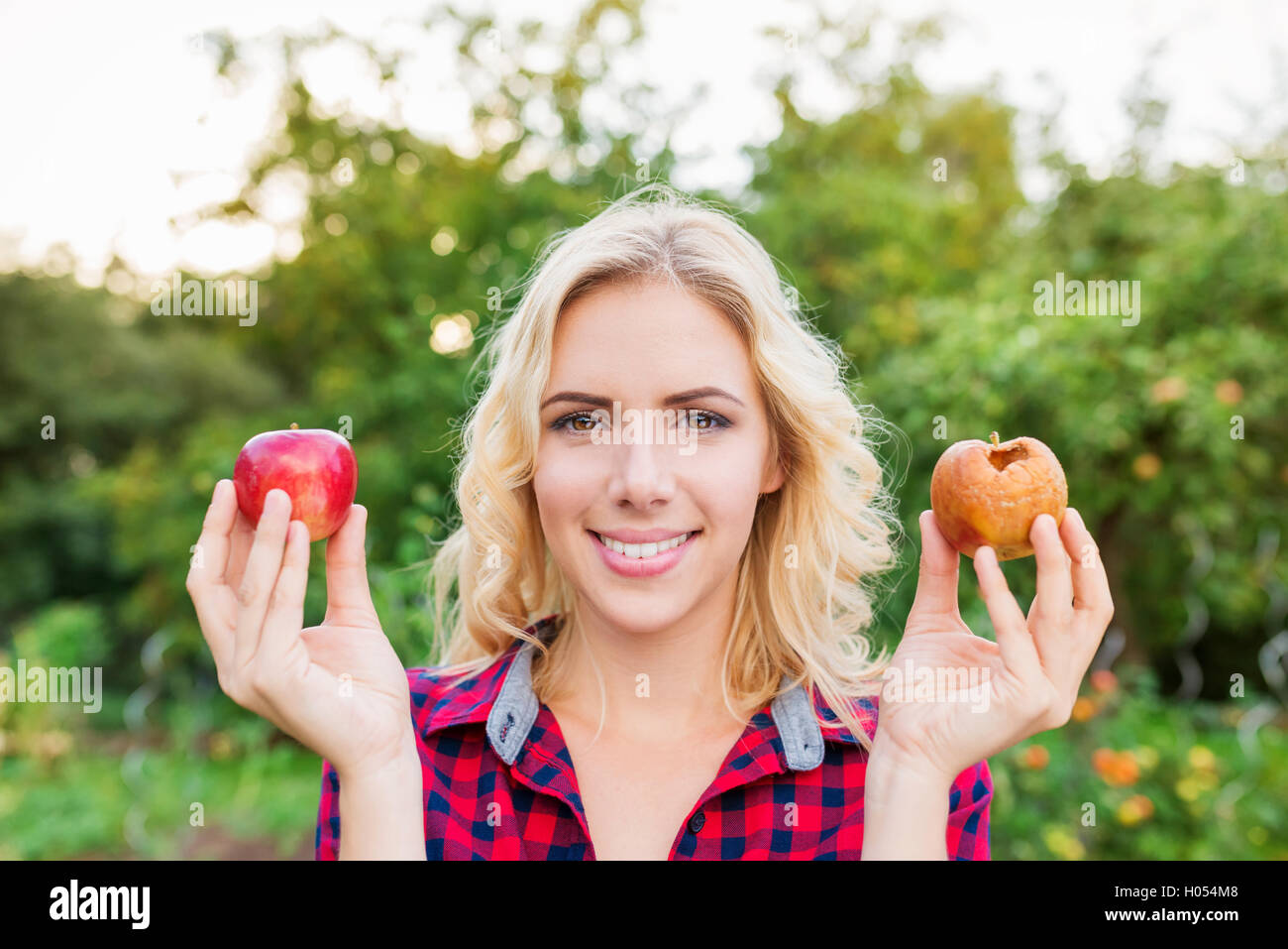 Beautiful woman holding rotten and good apple Stock Photo - Alamy