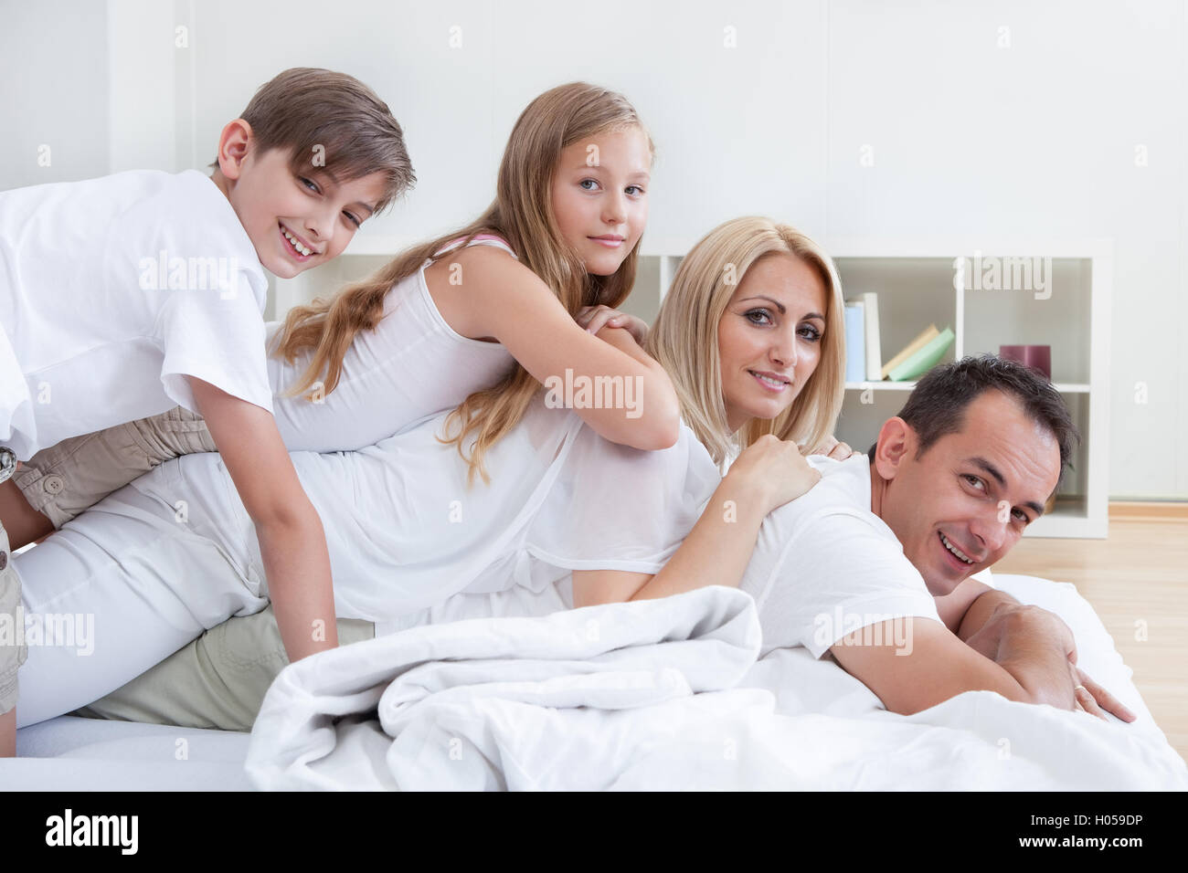 Happy Family With Two Children Lying Heaped On Bed Stock Photo - Alamy
