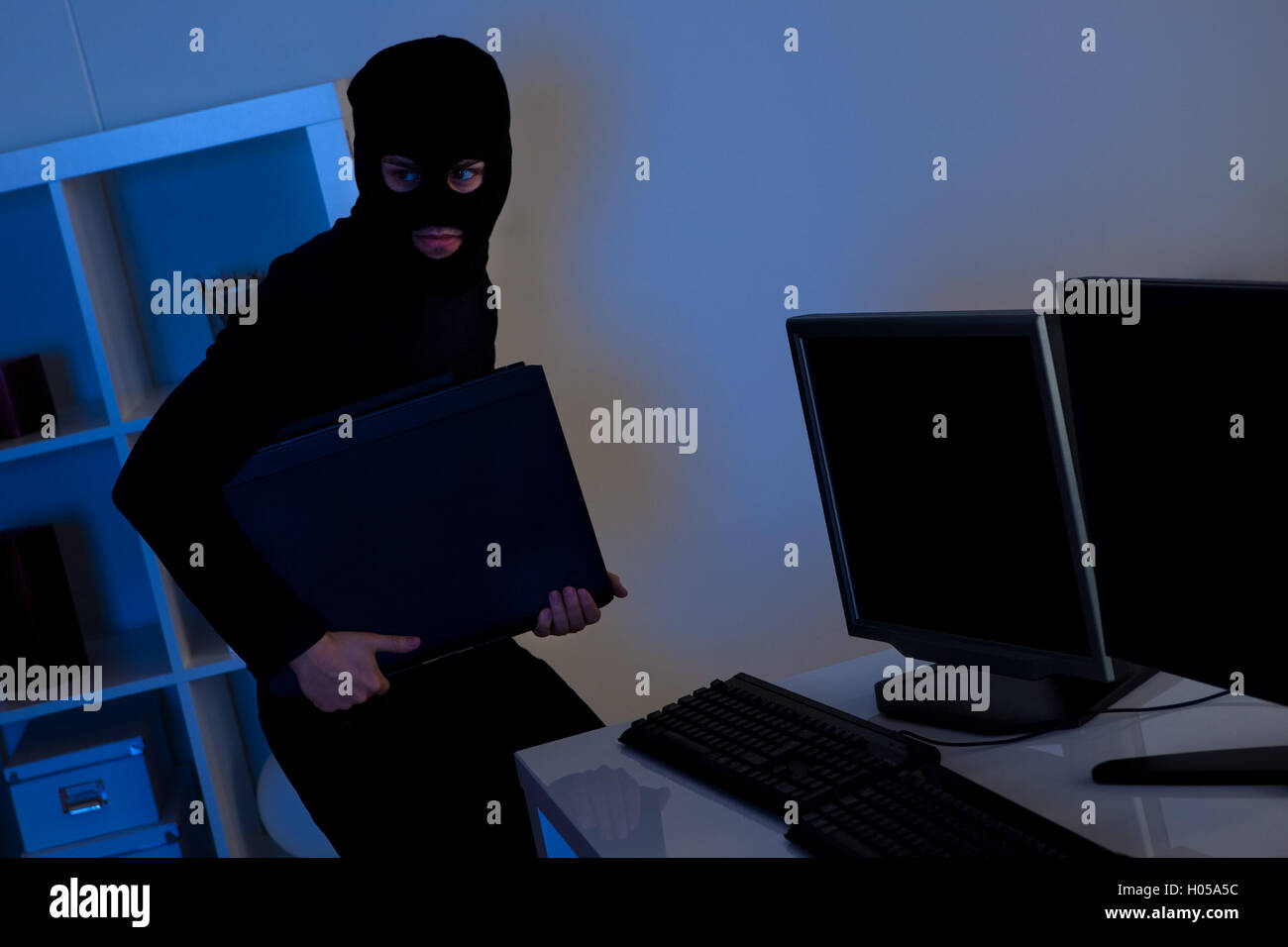 Thief steeling a computer Stock Photo - Alamy