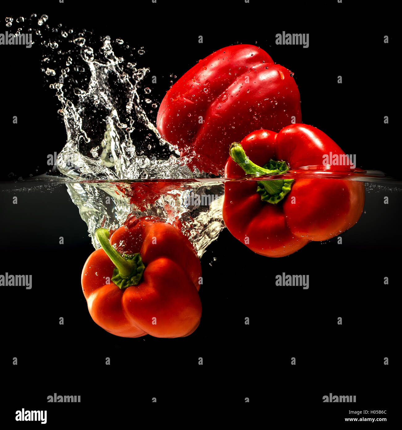 Group of bell pepper falling in water on black Stock Photo - Alamy