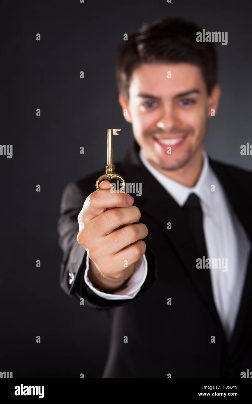 Smiling businessman holding a golden key Stock Photo - Alamy