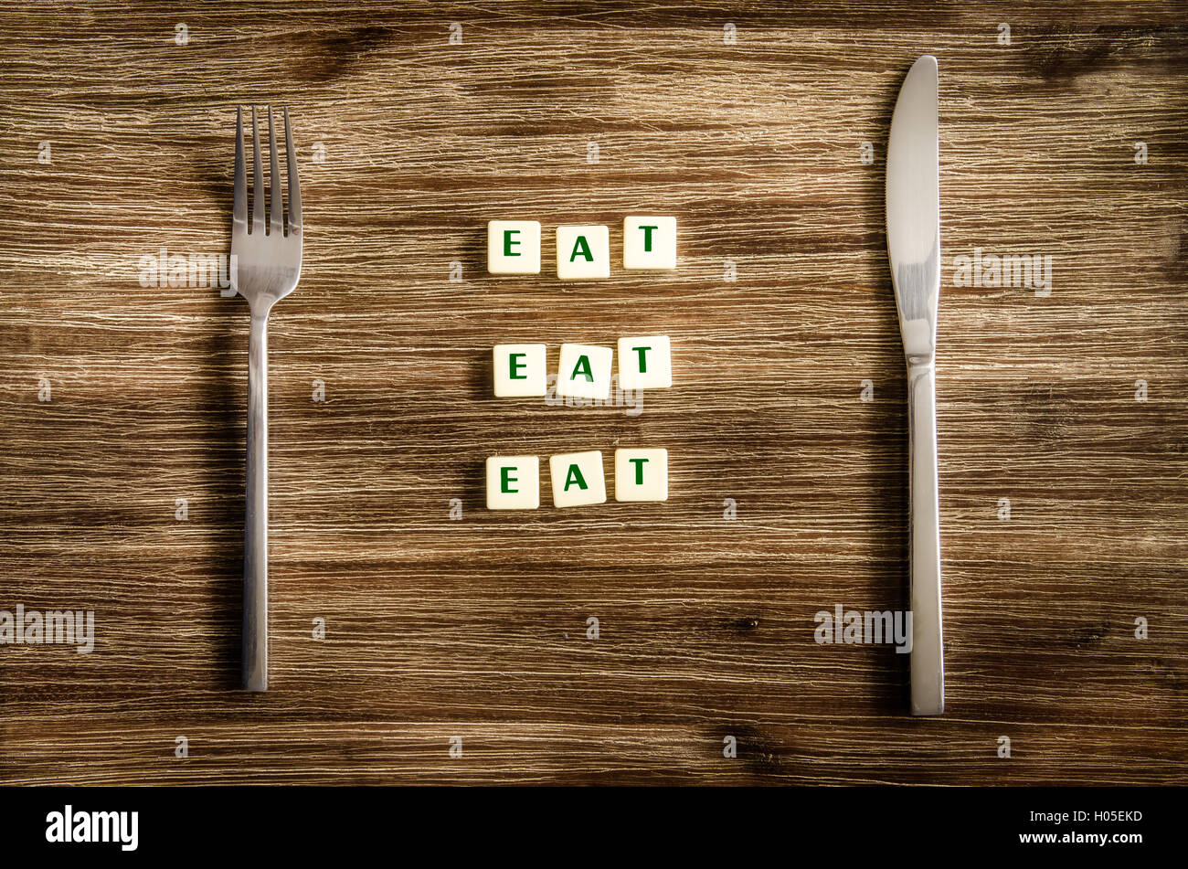 Knife and fork set on wooden table, sign saying Eat Stock Photo - Alamy