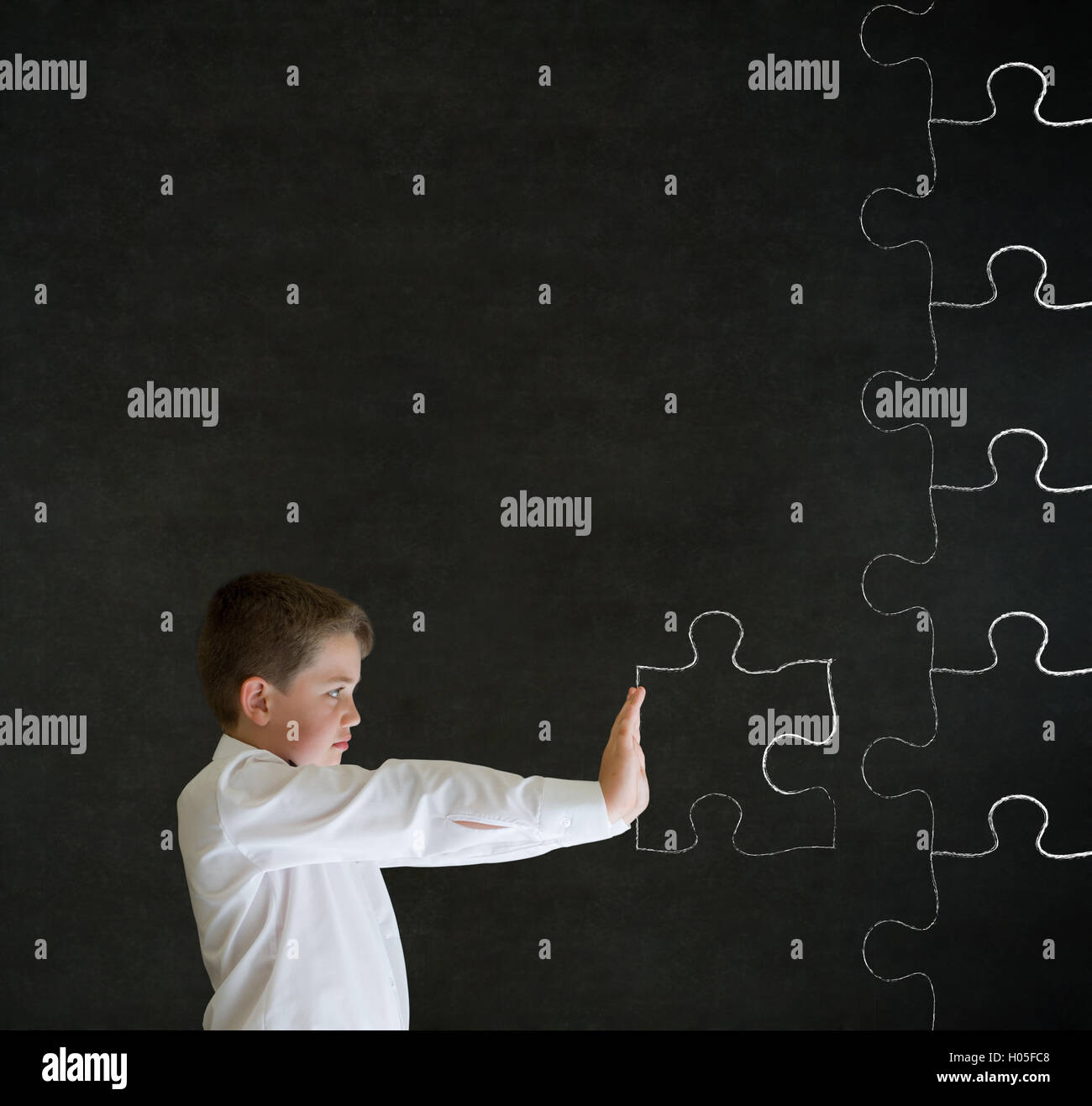 Boy pushing puzzle piece on blackboard background Stock Photo - Alamy