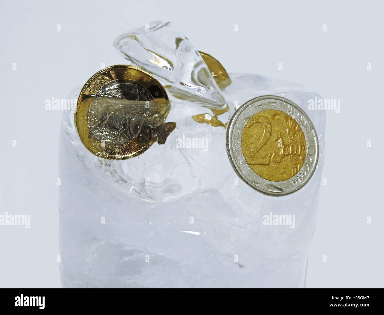 Cache euro coins in ice Stock Photo - Alamy