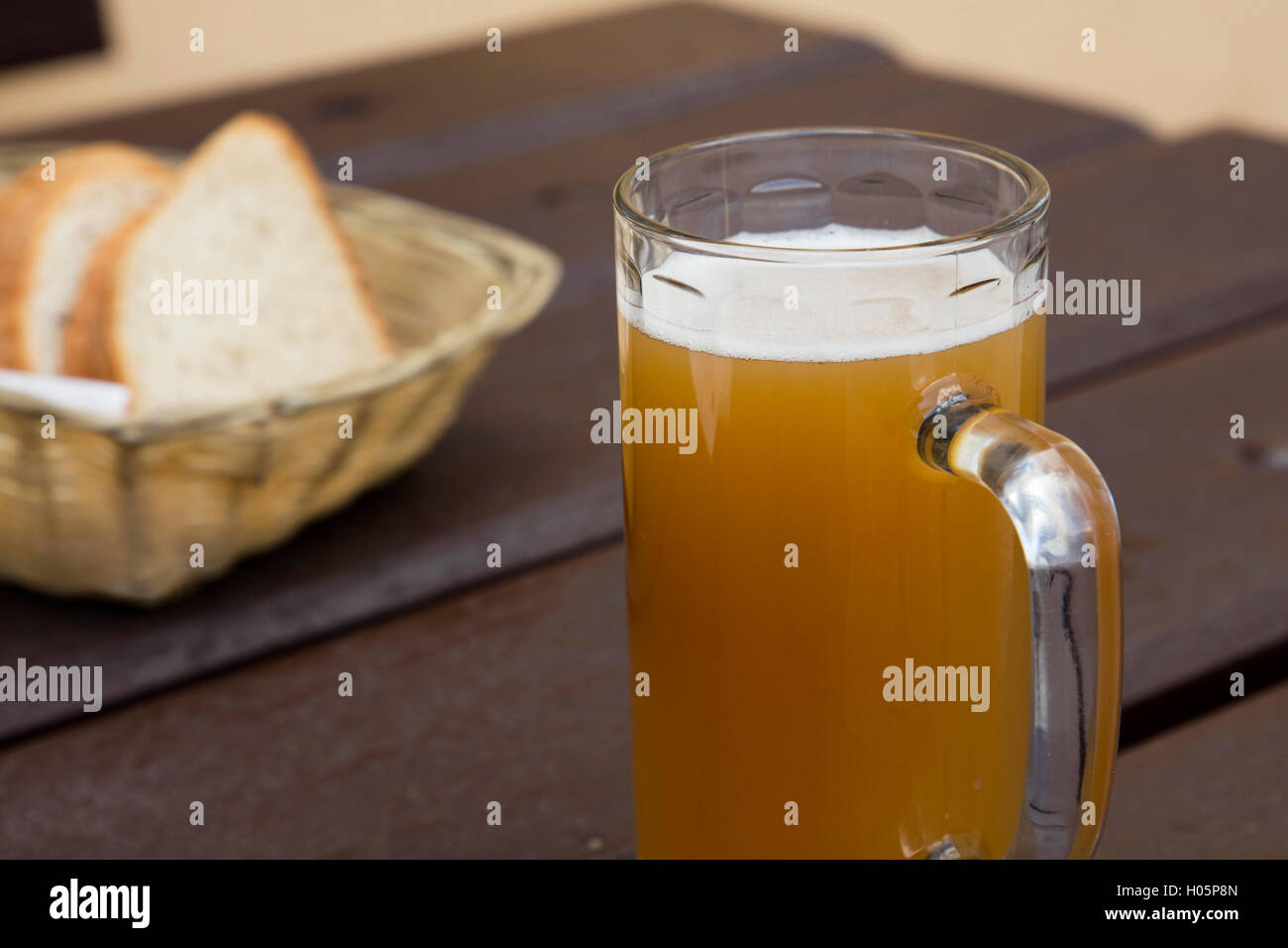 One glass of unfiltered craft draft wheat weizen beer and sliced bread ...