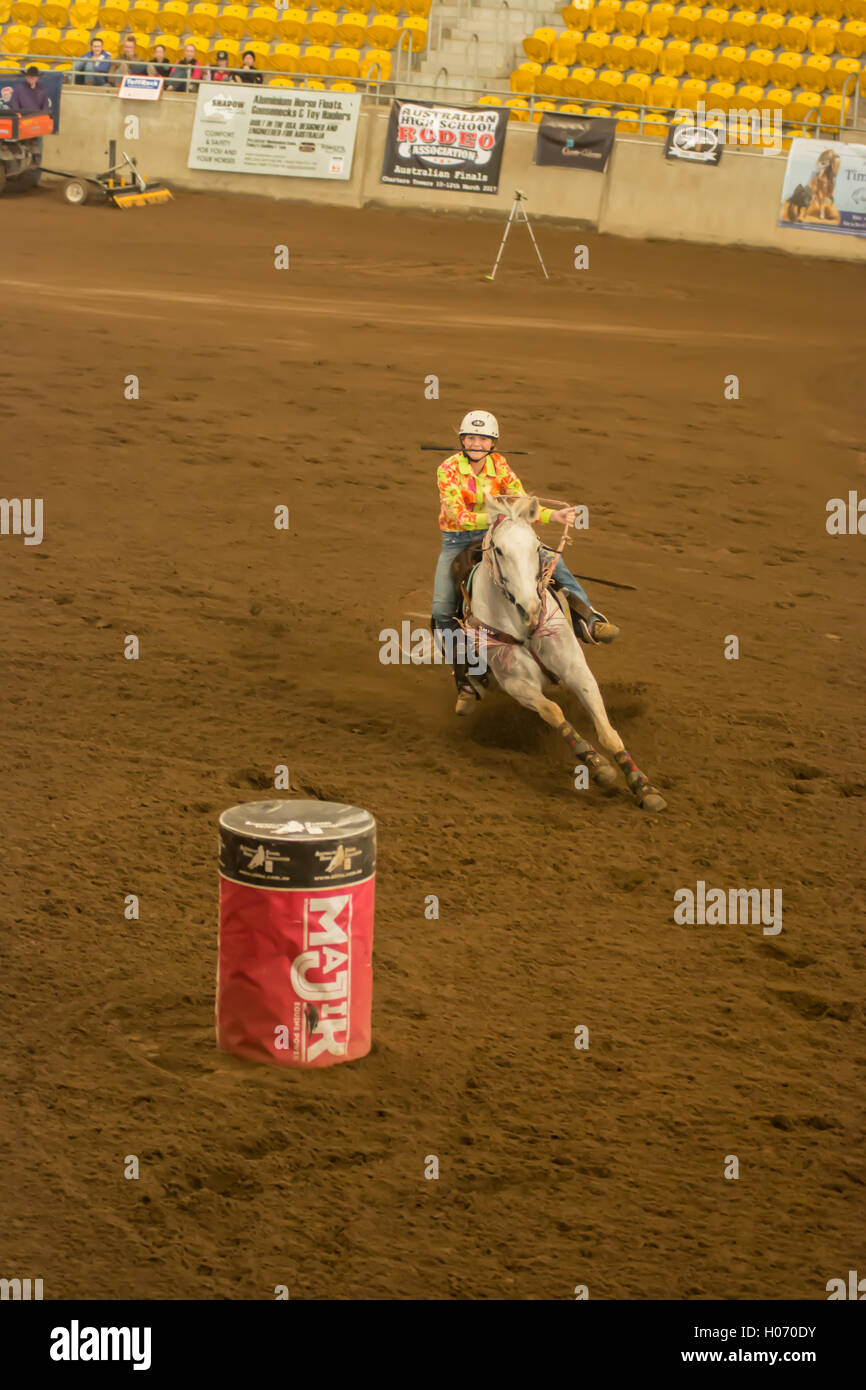 Barrel Racing at an Indoor Arena.Young girl riding with whip in mouth ...
