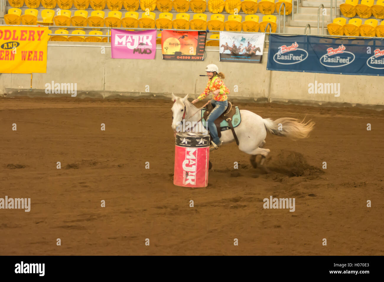 Barrel Racing at an Indoor Arena.Young girl riding with whip in mouth ...