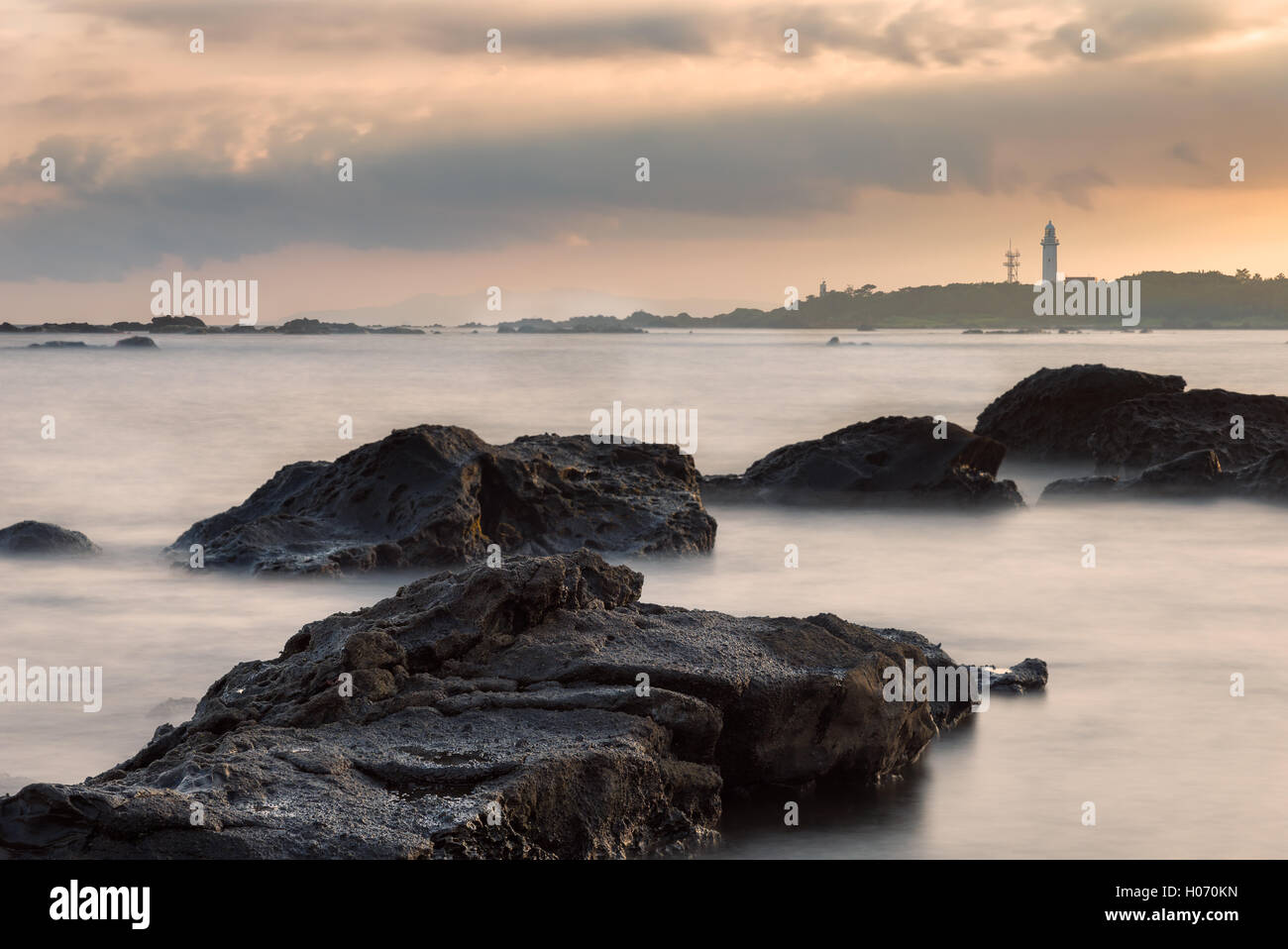 Sunset light hitting sea rocks by the beach with Nojimasaki lighthouse ...