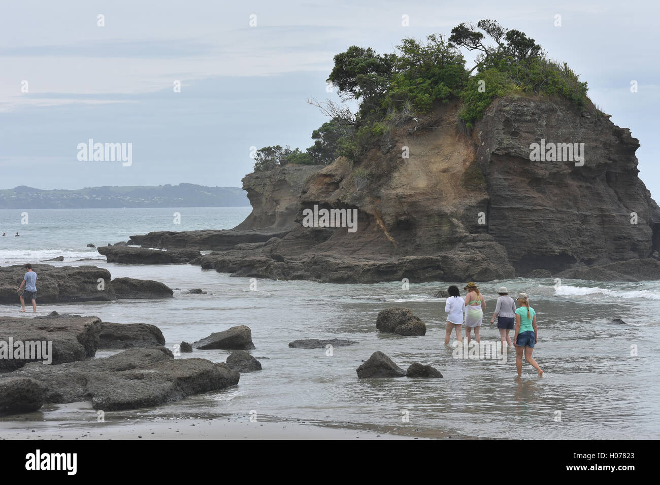 People wading in shallow water on beach among rock formations Stock ...