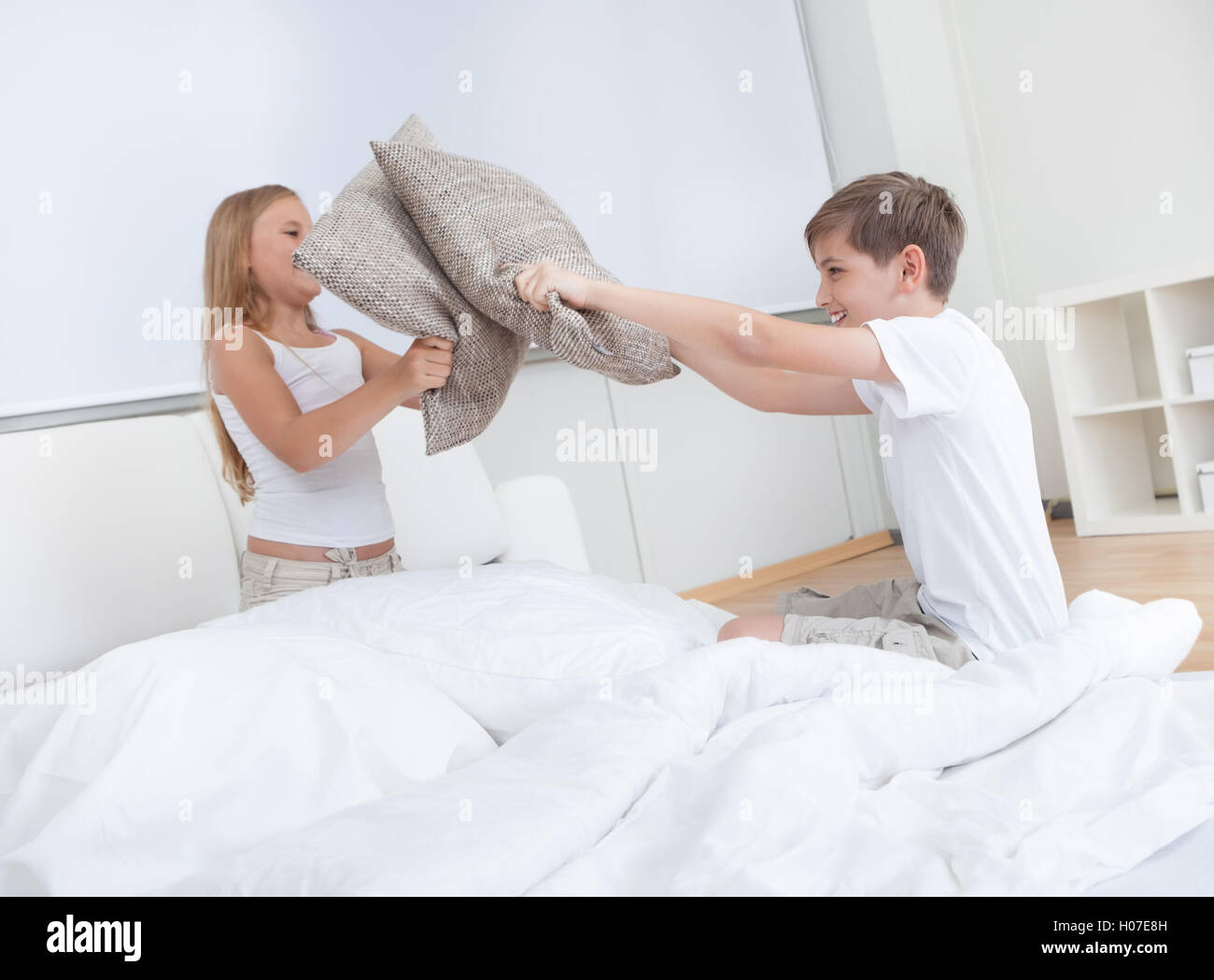 Siblings Having A Pillow Fight Together On Bed Stock Photo - Alamy