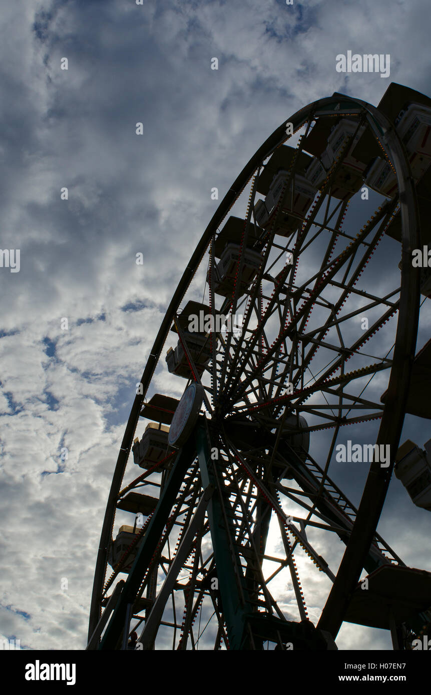 An almost full circle of the a ferris wheel is silhouetted against a ...