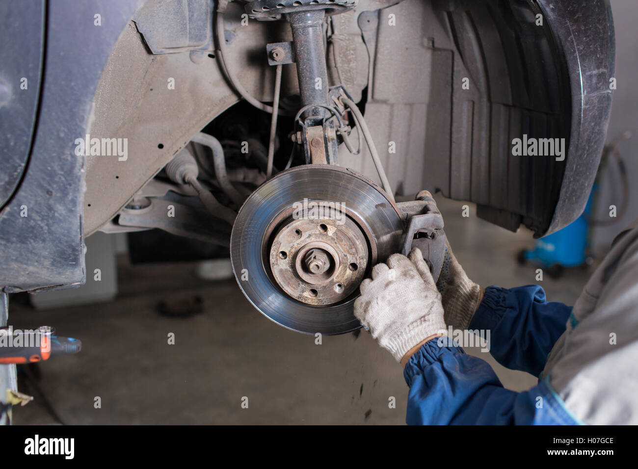 Brand new brake disc on car in a garage. Auto mechanic repairing a car ...