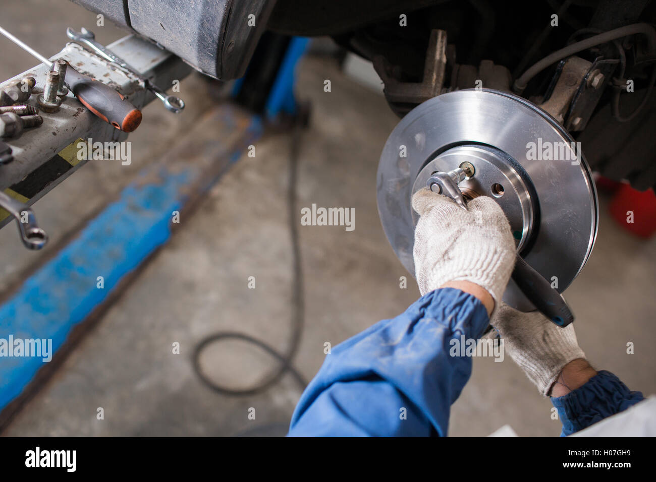 Brand new brake disc on car in a garage. Auto mechanic repairing a car ...